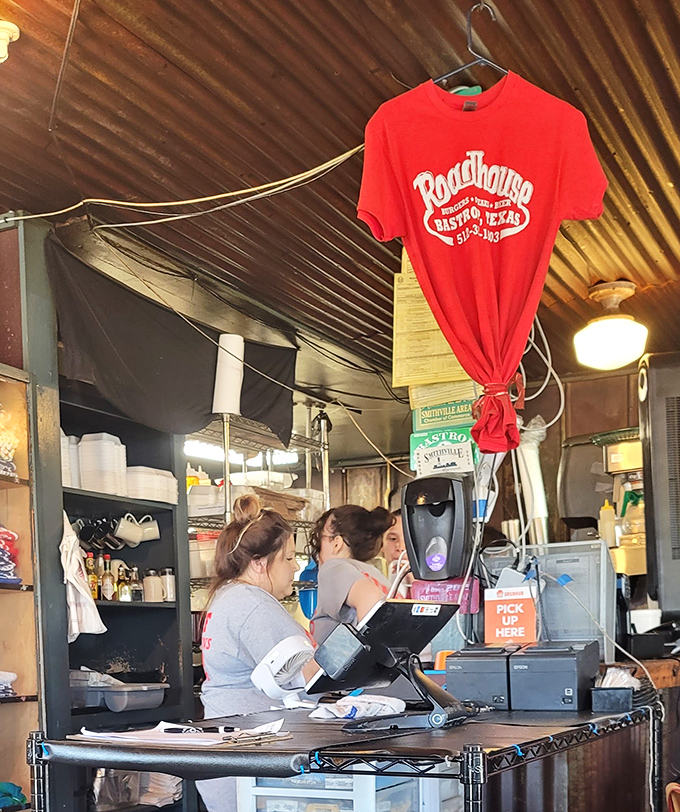 The beating heart of any great restaurant—staff who move with practiced efficiency while a red Roadhouse t-shirt stands sentinel overhead.