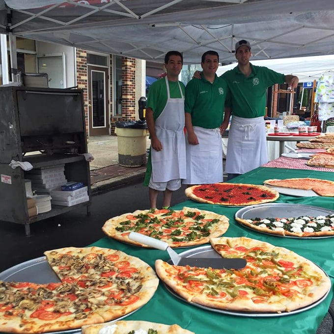 Pizza artisans at work during what appears to be a catering event. Fresh pies lined up like edible works of art, showcasing the variety of their craft.