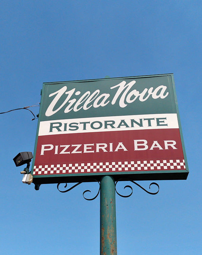 The iconic Villa Nova sign against blue Ohio skies—a beacon of hope for the hungry. Those Italian colors proudly announce: carbs and happiness await within.
