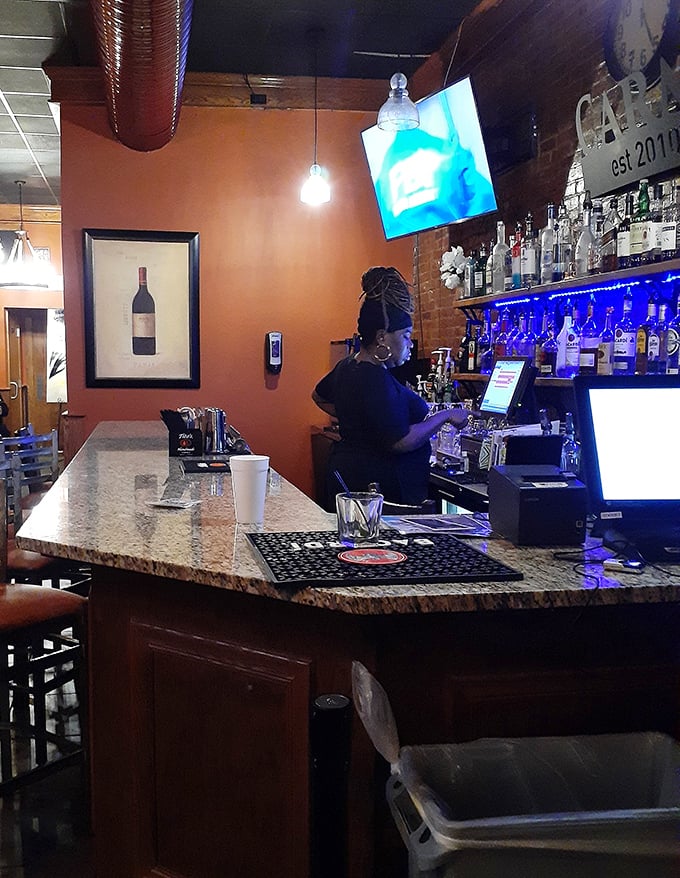 The bar area glows with blue light and promise—a place where cocktails complement comfort food in a marriage made in culinary heaven.