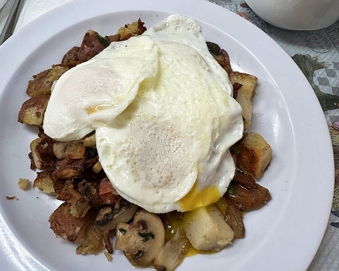 Perfectly cooked eggs atop a mountain of home fries – proof that sometimes the best breakfast architecture is a beautiful mess.