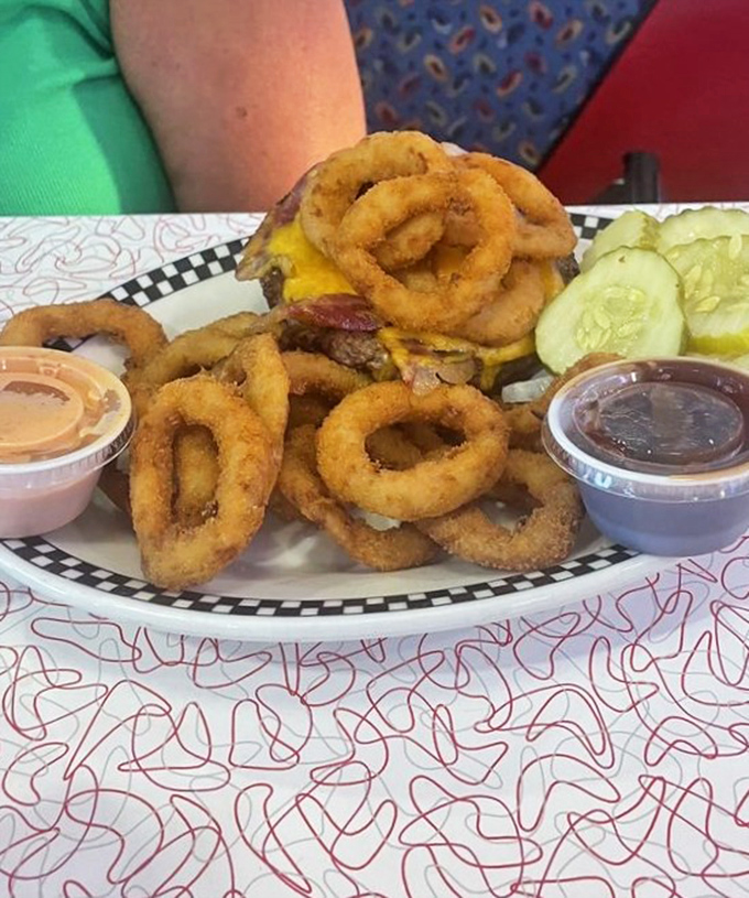 A burger crowned with onion rings isn't excess—it's ambition. Those pickle slices stand guard like sentinels of tang against the richness.