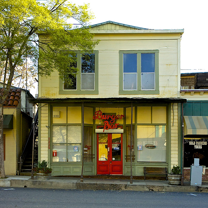 The Burger Bar's cherry-red door beckons like a dinner bell, promising comfort food in a building that's witnessed generations of hungry travelers.
