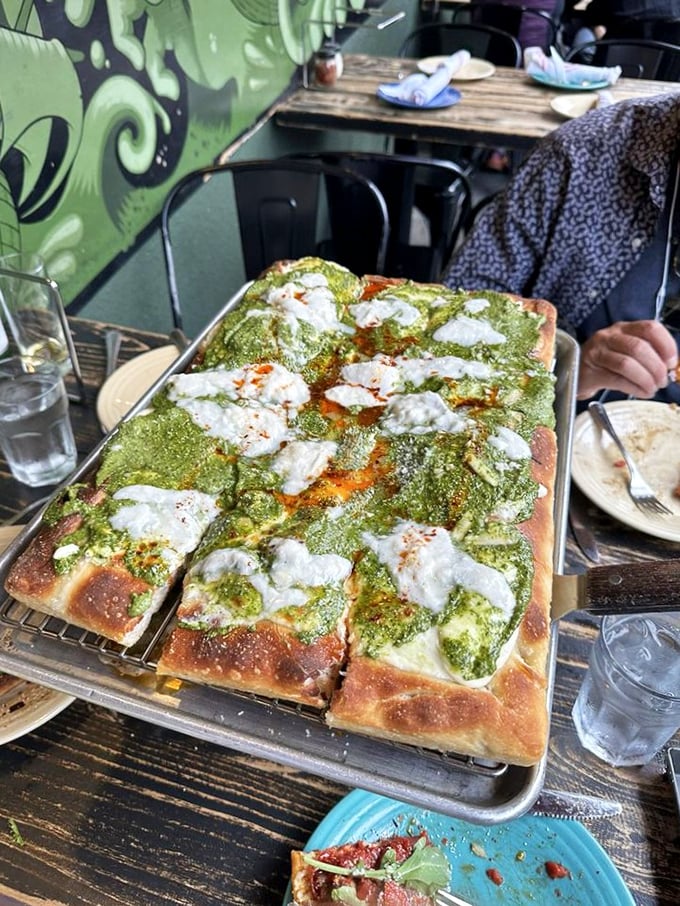 Not all heroes wear capes—some come covered in vibrant pesto, dotted with creamy cheese islands that melt into a sea of flavor.