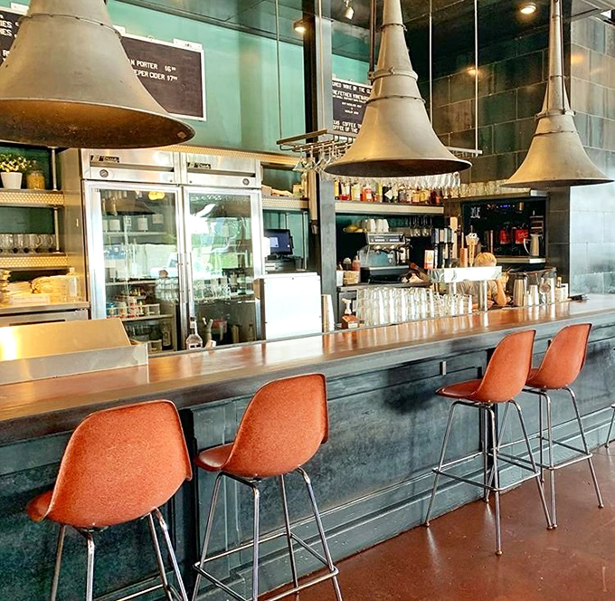 The counter seating offers front-row tickets to the culinary show, with those distinctive orange chairs adding mid-century flair.