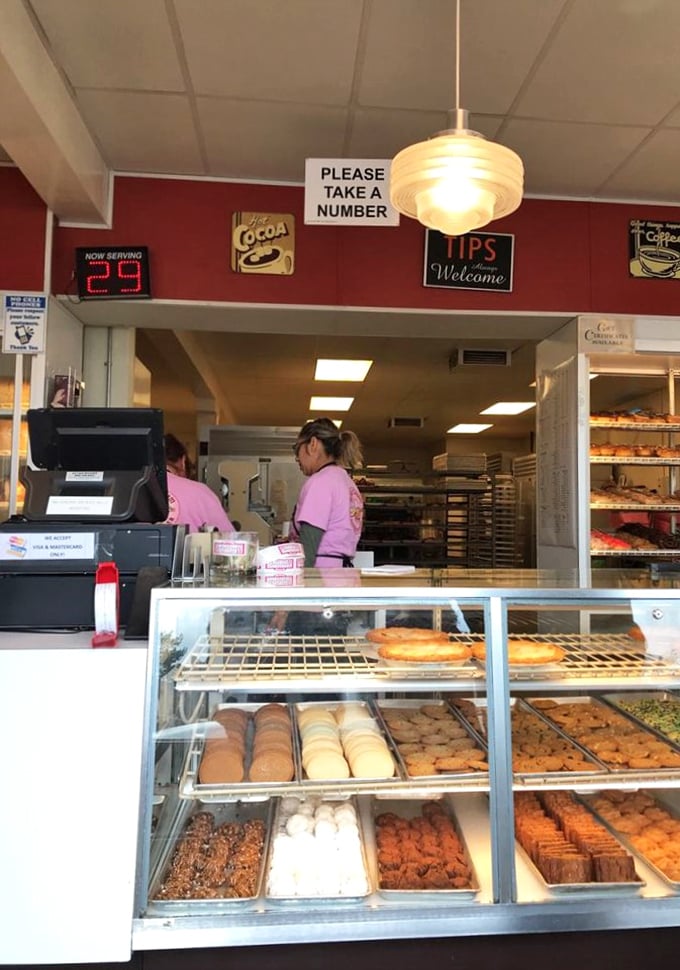 The counter service experience—where numbered tickets, vintage signs, and display cases full of temptation create the perfect diner atmosphere.