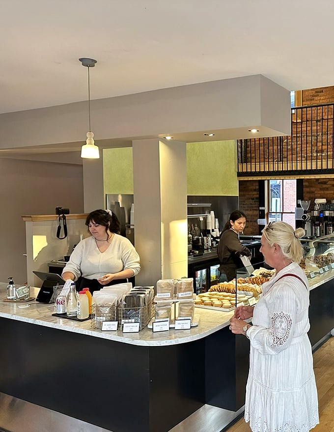 At the counter, pastries pose like celebrities on a marble runway, each one vying to be your next indulgence.