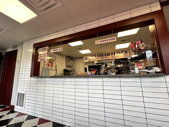 The ordering counter—where dreams are placed and fulfilled. White subway tiles gleam with the promise of ice cream flavors to come.