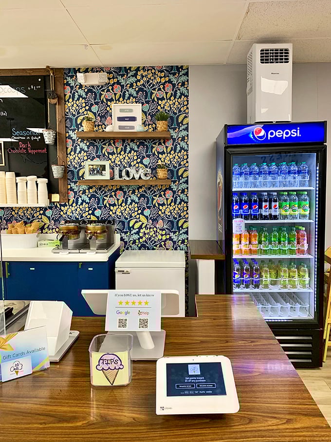 Behind this counter, magic happens daily. The floral wallpaper backdrop adds a touch of whimsy to the serious business of ice cream.