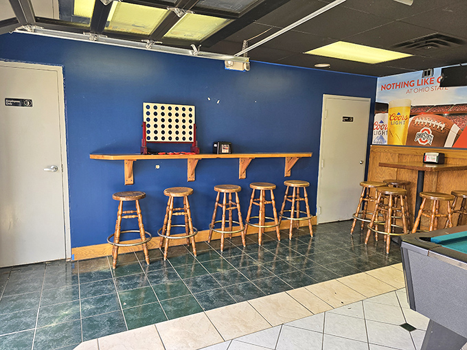 The counter seating area with its bright blue wall and Connect Four game—where waiting for your pizza becomes part of the experience.