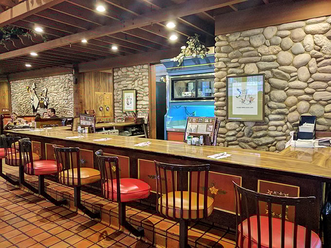 The counter seating offers front-row tickets to the culinary show, with stone walls and wooden beams creating a cozy tavern atmosphere.