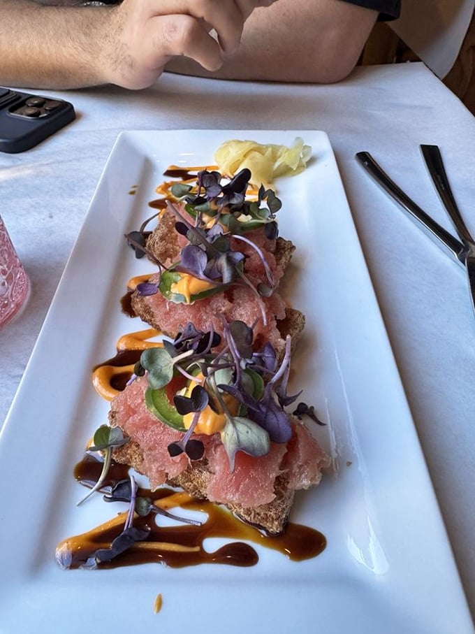 Tuna tartare elevated with microgreens and artistic sauce drizzles—proof that some of the best food never meets a flame.