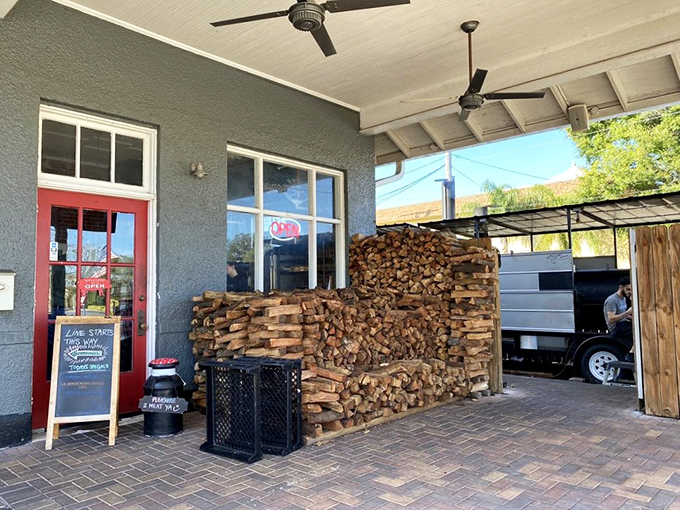 The woodpile that tells you everything you need to know – this place isn't messing around. That red door might as well be the gateway to meat heaven.