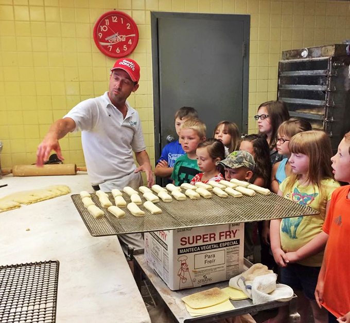 Future donut connoisseurs get a behind-the-scenes education. Their faces show the appropriate reverence for this sacred culinary tradition.