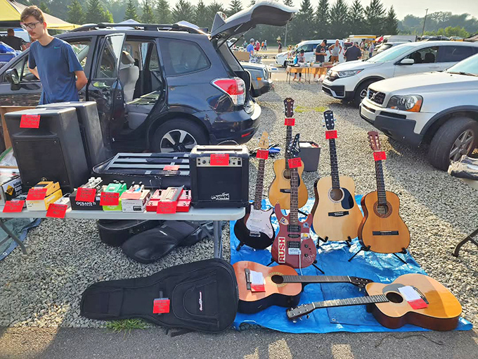 Six-string dreams laid out on blue tarps. From campfire sing-alongs to teenage rock star ambitions, these guitars await their next chord progression.