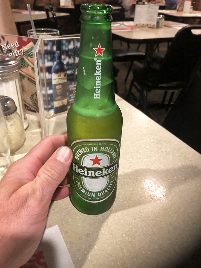 A cold Heineken awaits its destiny—to wash down pizza that deserves a proper beverage companion. Some matches are just meant to be.