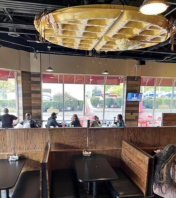 Wooden booths that have witnessed countless morning conversations, all under the watchful eye of that magnificent waffle in the sky.