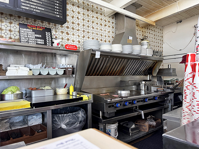 The open kitchen reveals the battlefield where burger magic happens—stainless steel, sizzling grills, and organized chaos.