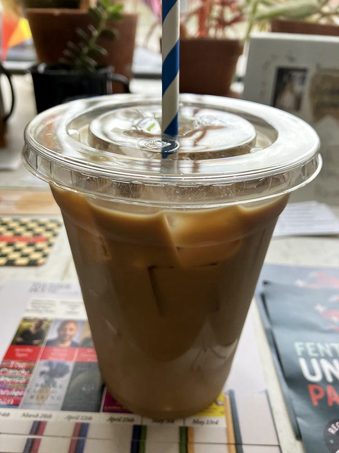 Iced coffee served with a jaunty blue straw—the caffeinated sidekick to your pastry adventure. Newspaper optional, daydreaming mandatory.