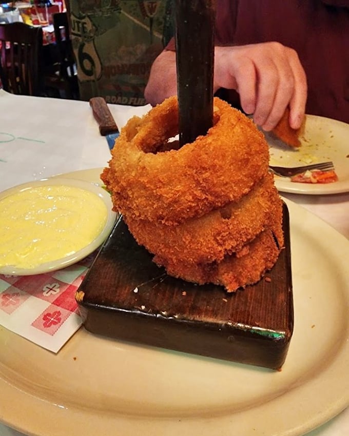 These onion rings aren't just stacked—they're practically architectural, with a golden crust that shatters with each bite and a side of heavenly dipping sauce.