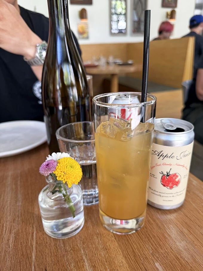 Even the non-alcoholic options deserve respect. Apple juice sparkles alongside wildflowers, proving refreshment needn't always involve fermentation.