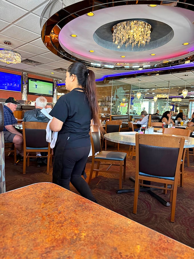 Under the watchful glow of that showstopping chandelier, staff navigate the dining room with the precision of dancers who know every step by heart.