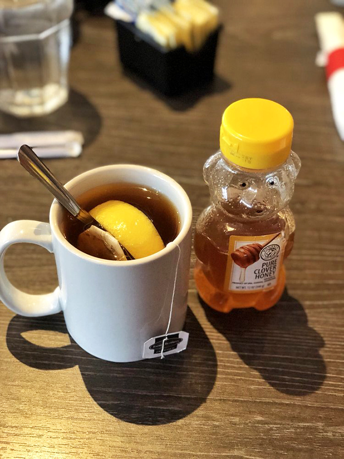 Hot tea served with honey in a bear bottle—because sometimes the simplest pleasures, like squeezing that little bear, bring the most joy.