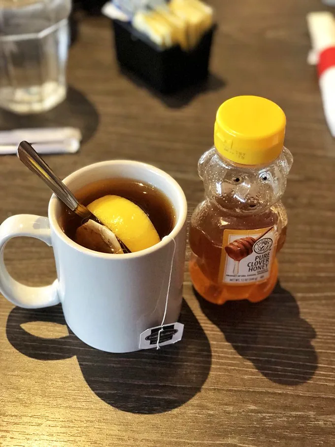 Hot tea served with honey in a bear bottle—because sometimes the simplest pleasures, like squeezing that little bear, bring the most joy.