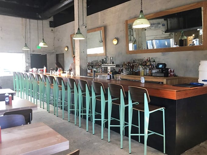 The mint-green bar stools pop against the rustic wood bar – a front-row seat to the liquid accompaniments for your meat marathon.