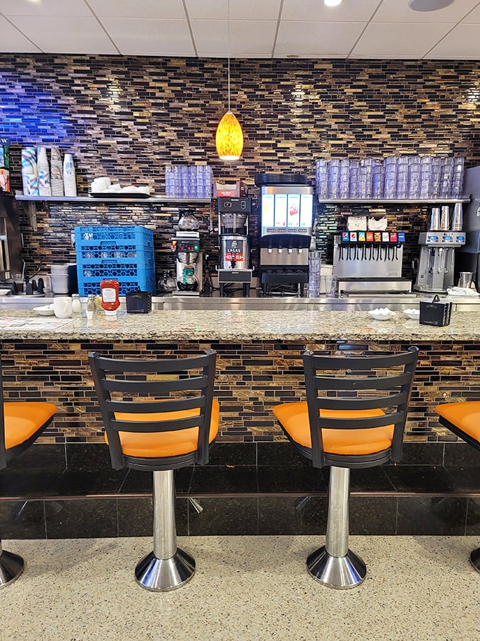 The bar stools aren't just seating—they're front-row tickets to the breakfast show. Those orange cushions have witnessed countless coffee refills and life stories. 