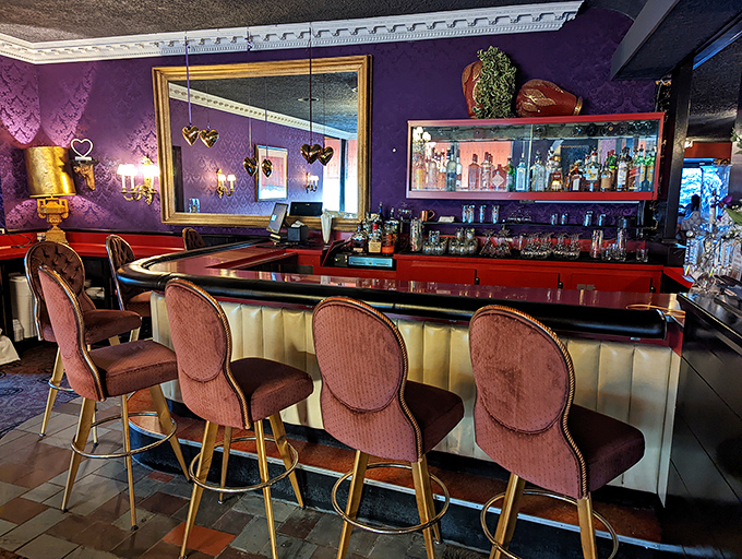 The bar area strikes that perfect balance between swanky and comfortable—purple walls, red accents, and padded stools that invite you to stay awhile.