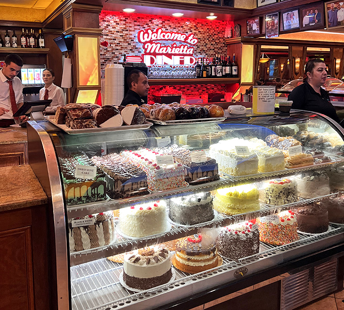 The dessert case—where willpower goes to surrender. Each cake stands like a sugary skyscraper, architectural marvels of butter and flour.