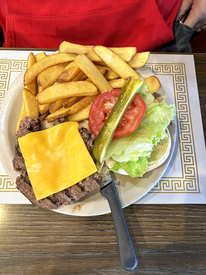 A proper diner cheeseburger with fries that could make a fast-food joint weep with inadequacy. That pickle spear is standing guard like a delicious sentinel.