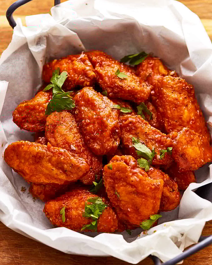 These wings aren't messing around—glossy with sauce and garnished with fresh herbs, they're the kind that silence conversation as everyone focuses on the next bite.
