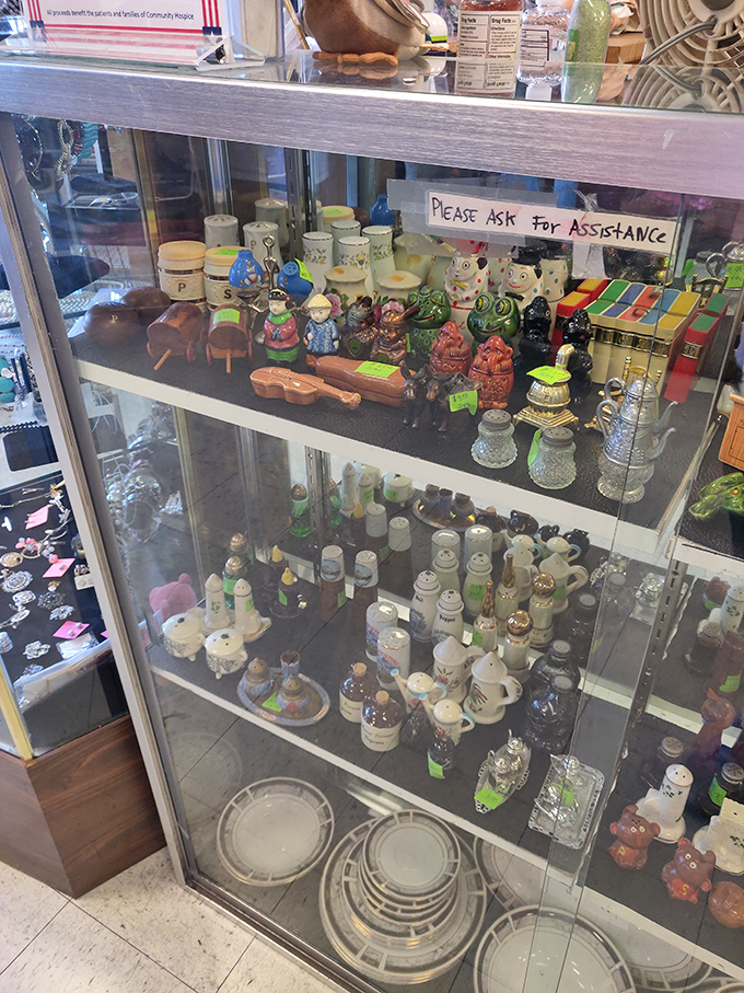 Miniature collectibles behind glass—like a museum of tiny treasures where "Please ask for assistance" really means "Yes, you can afford these!"