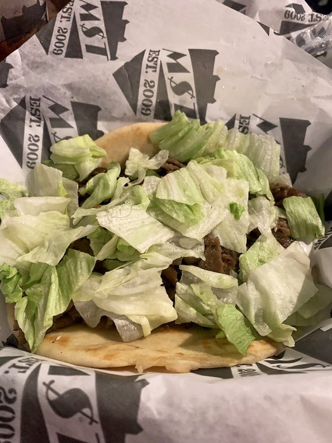 Fresh lettuce adds a crisp counterpoint to what lies beneath—a culinary strategy as old as time but executed here with particular finesse.