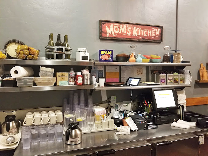 The "Mom's Kitchen" sign says it all – this is comfort food territory. The organized chaos of a working kitchen where magic happens daily. 