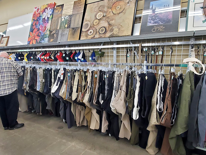 Where denim meets decor—this cozy thrift aisle pairs gently worn jeans with gallery-worthy flair overhead. It’s like strolling through someone’s curated closet… with better prices.