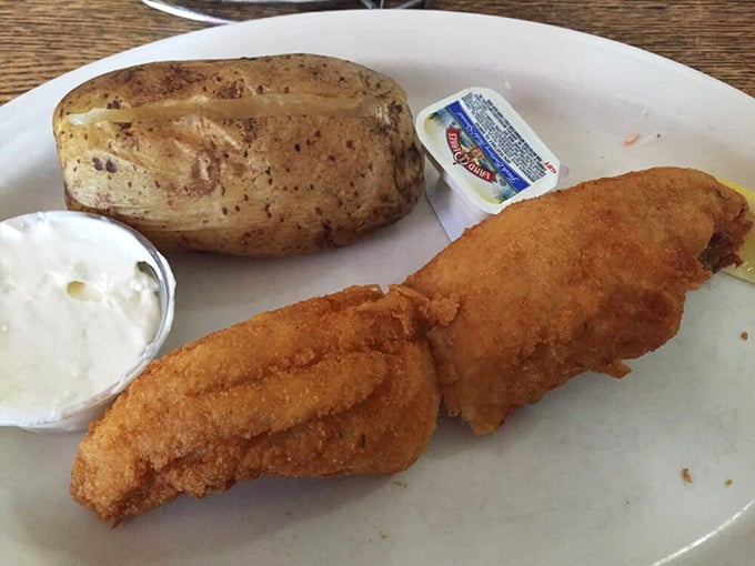 A perfectly golden walleye fillet with a baked potato on the side—Midwest lake-to-plate perfection that needs nothing more than a squeeze of lemon.
