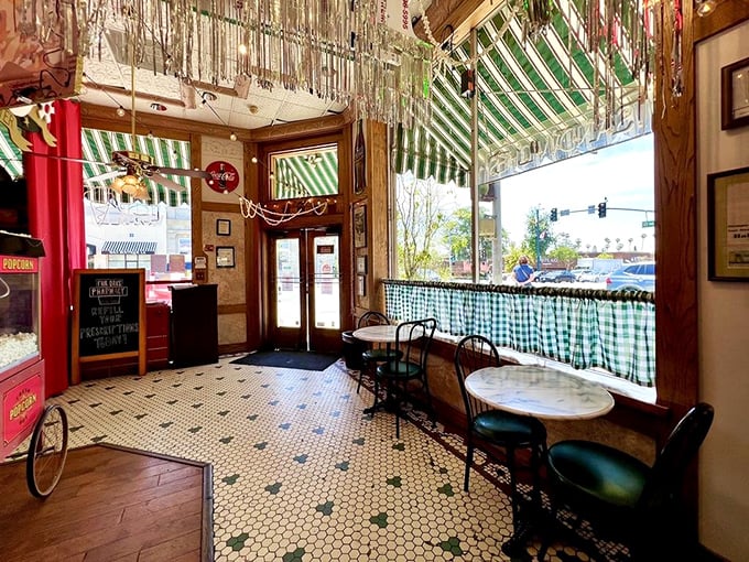Green striped awnings frame the perfect people-watching perch, where every table tells a different story.