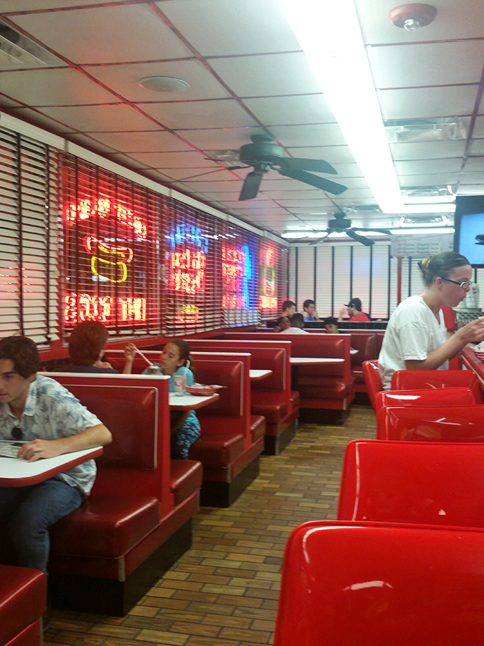 Neon signs illuminate red booths like beacons of comfort, guiding hungry travelers to the promised land of all-day breakfast.