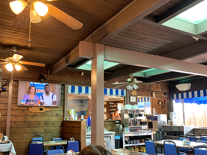 Ceiling fans lazily spin above wooden beams and nautical-blue accents, creating an atmosphere as relaxed as a Sunday morning.