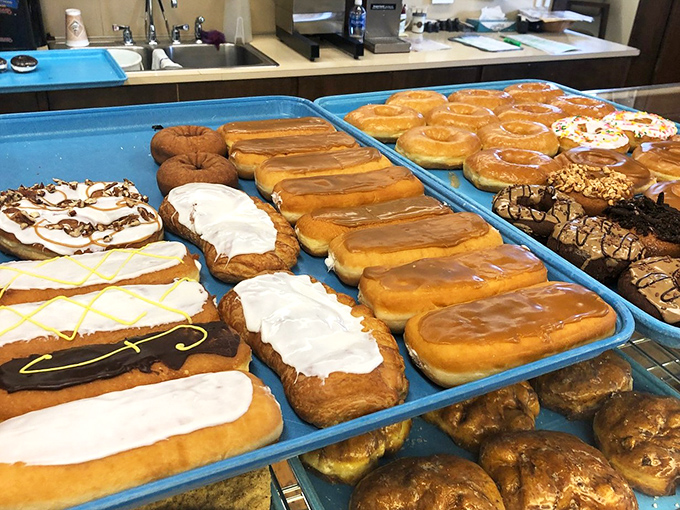 Long trays of donuts in various states of delicious dress—some glazed, some frosted, all plotting to destroy your willpower with surgical precision.