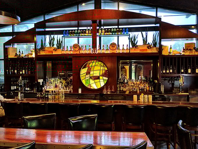 The bar area gleams with amber bottles and warm wood tones—a liquid library of spirits waiting to complement your meal.