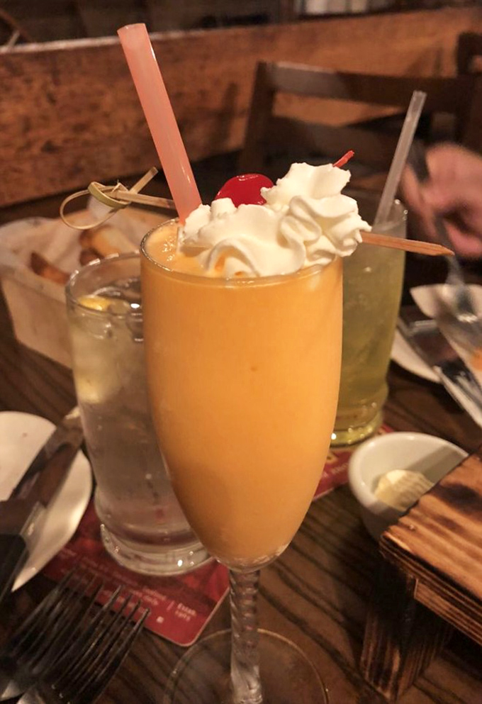 This isn't just a Bellini—it's sunshine in a glass, topped with whipped cream and a cherry, because sometimes cocktails deserve dessert treatment too.