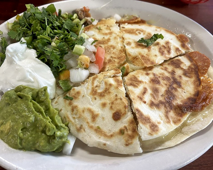 Quesadillas that achieve the golden ratio of crisp exterior to molten interior. That cilantro garnish isn't just pretty – it's the perfect counterpoint to all that cheese.
