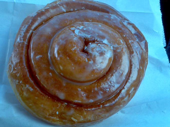 The cinnamon roll donut—a spiral of happiness with glaze catching light like morning dew on a spider's web.
