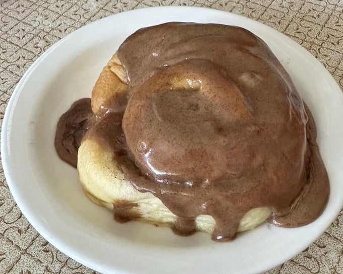 This cinnamon roll isn't just drowning in chocolate—it's enjoying a luxurious spa treatment of the sweetest kind.