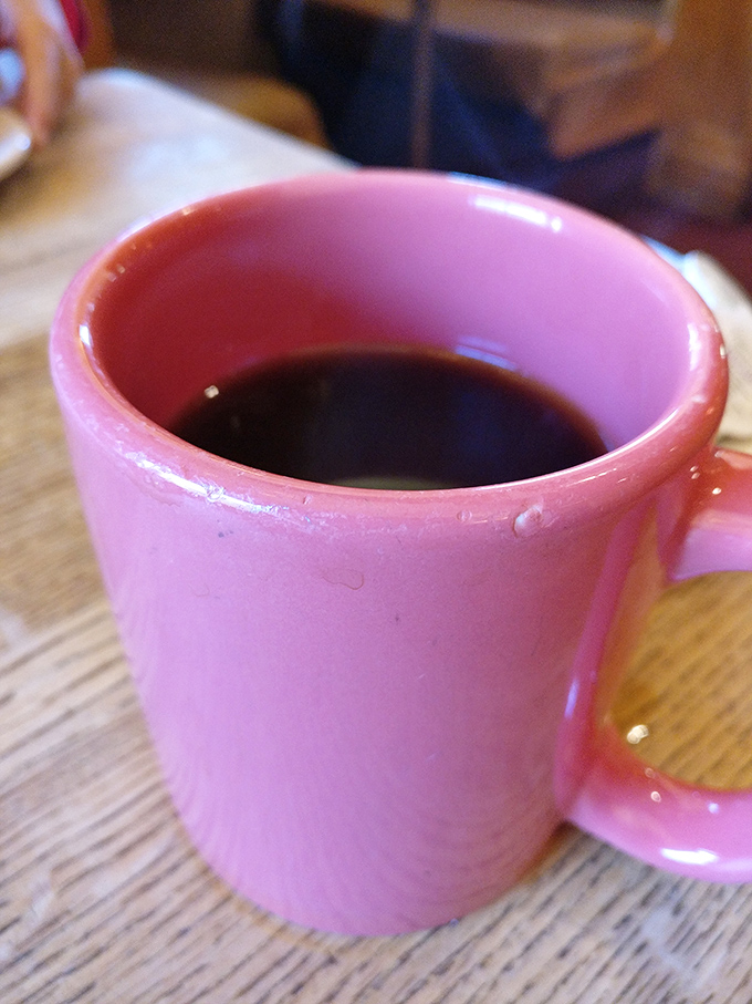 The pink coffee mug adds a touch of whimsy to your caffeine ritual. In diners, coffee isn't just a beverage—it's a constitutional right.