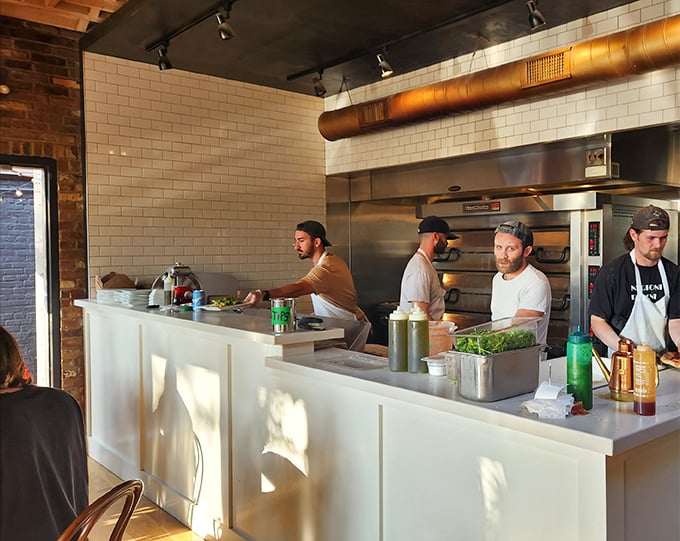 The open kitchen isn't just functional – it's dinner and a show, where pizza-making becomes performance art worth watching.